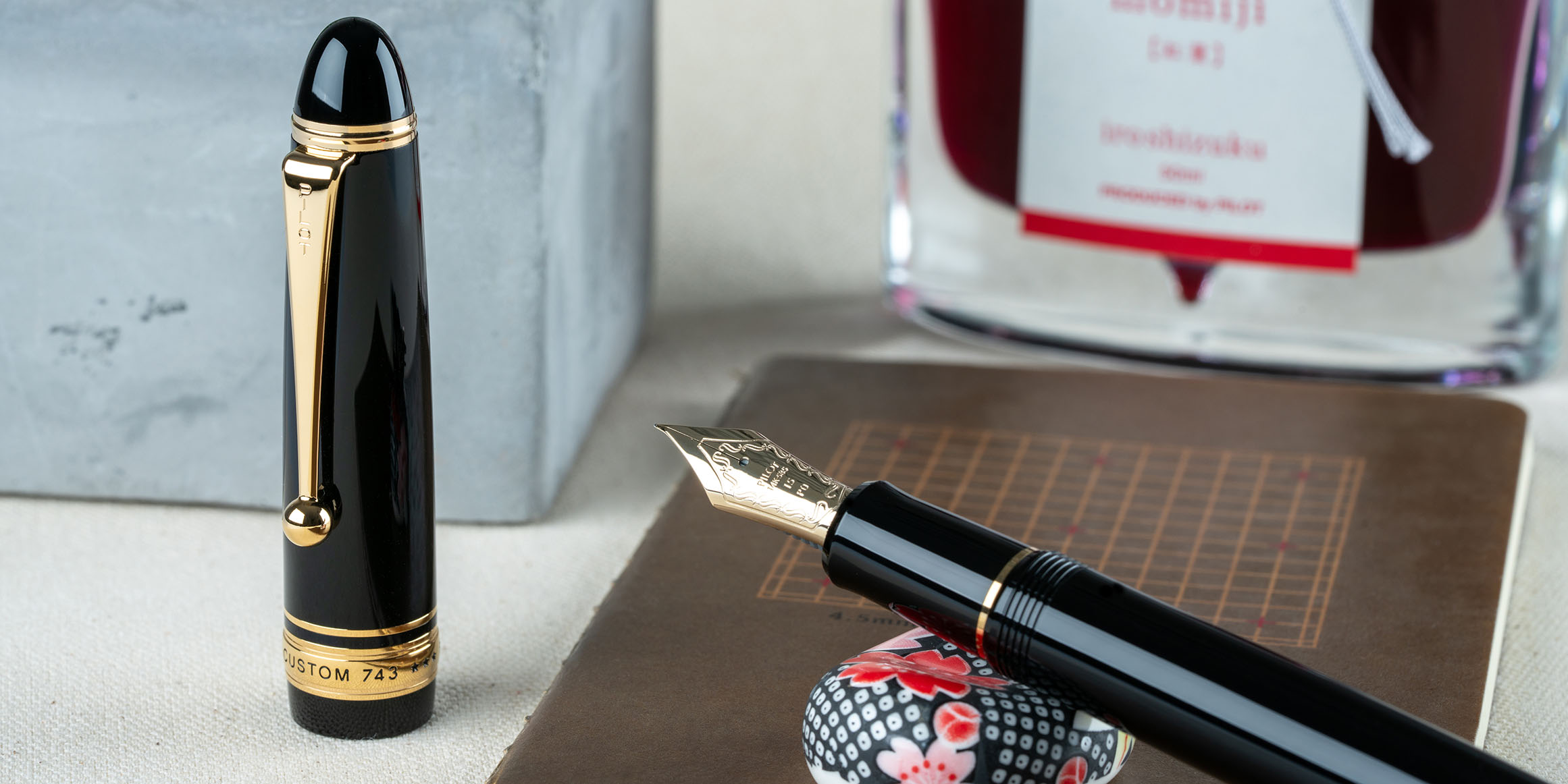 custom 743 black with gold fountain pens with ink behind - Pen Chalet
